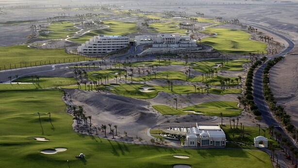 Um campo de golfe com um clube, vários edifícios e uma paisagem desértica.
