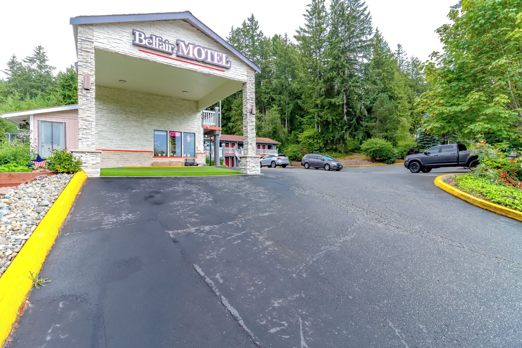 Um motel com fachada de pedra, entrada coberta e área de estacionamento.