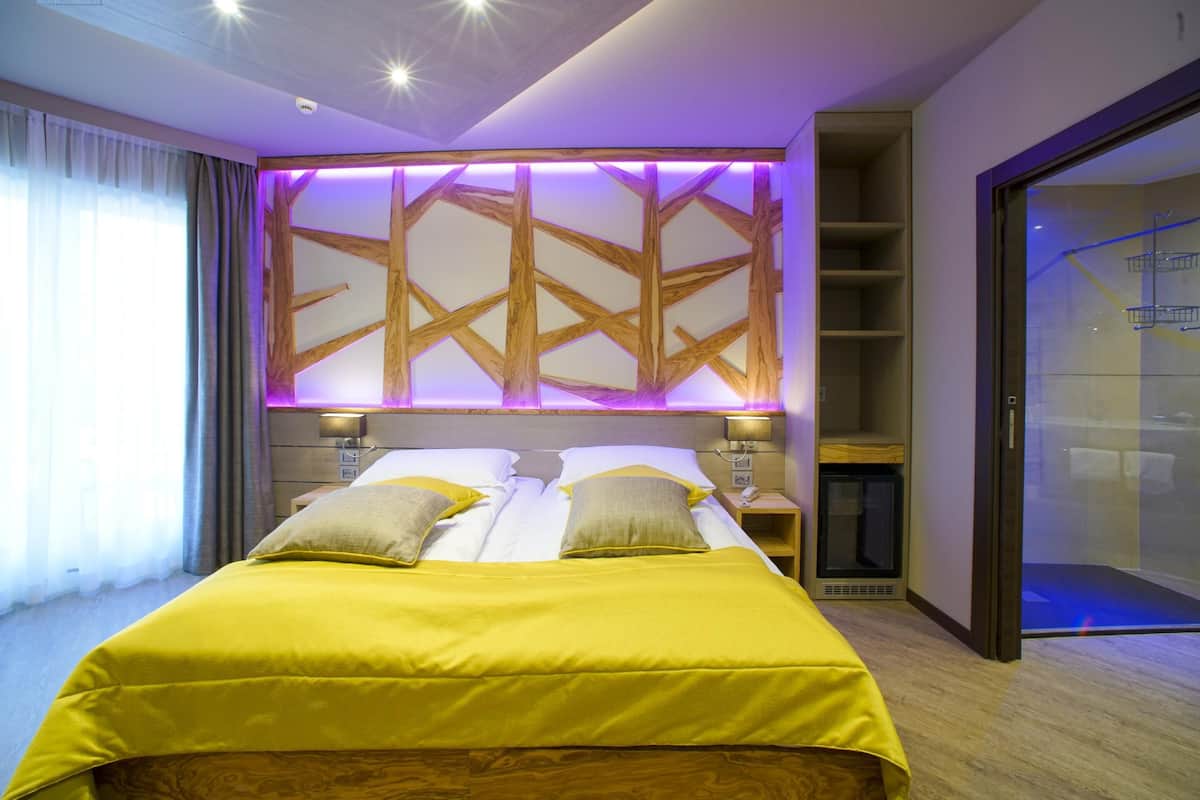 Quarto moderno com cama, mesas de cabeceira e estante embutida.