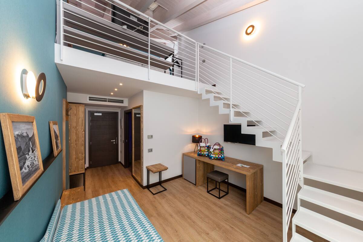 Um interior moderno com escada, uma mesa e uma cama.