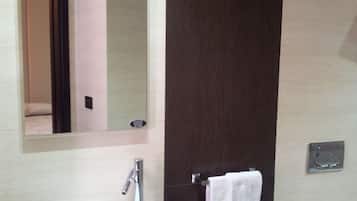 Um banheiro com uma pia redonda, um espelho, porta-toalhas e um vaso sanitário.
