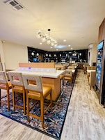 Um hall de hotel com área de bar, assentos e carpete estampado.