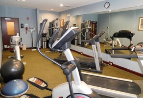 Ginásio com máquinas de cardio, espelho e bolas de exercício.