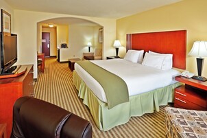 Quarto de hotel com uma cama grande, escrivaninha com telefone, uma cadeira e televisão.