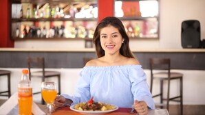 Uma pessoa sentada à mesa com um prato de comida, um copo de suco de laranja e uma garrafa de suco de laranja.