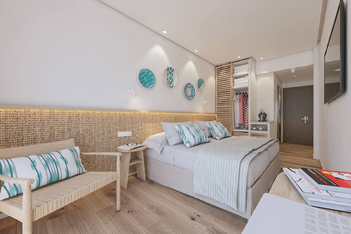 Quarto moderno com uma cama grande, cabeceira de madeira, mesa de cabeceira e um banco.
