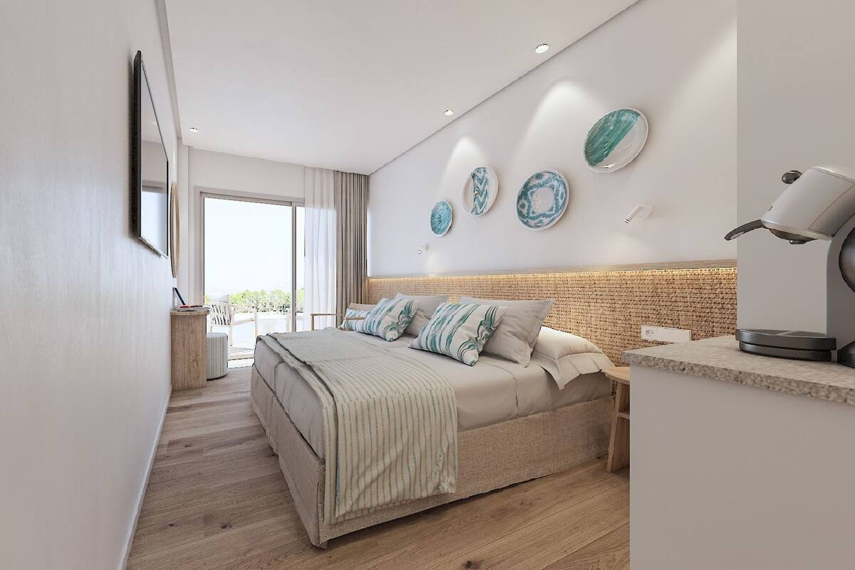 Quarto moderno com cama grande, escrivaninha pequena e vista para o exterior.