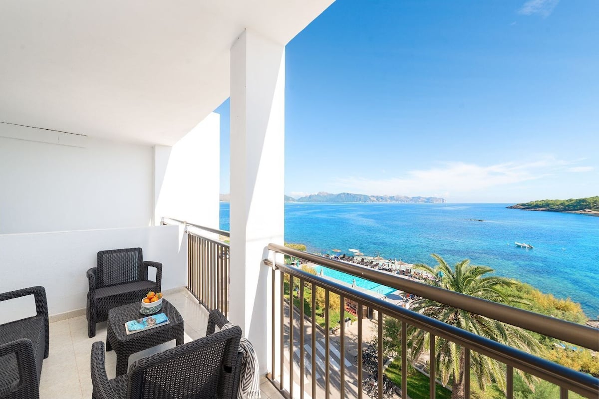 Varanda com mobiliário de vime e vista para o mar.
