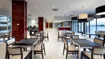 Um restaurante moderno com um balcão extenso e várias mesas e cadeiras.