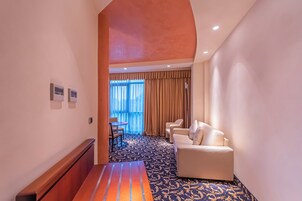Quarto de hotel com um banco de madeira, um sofá e uma mesa de jantar.