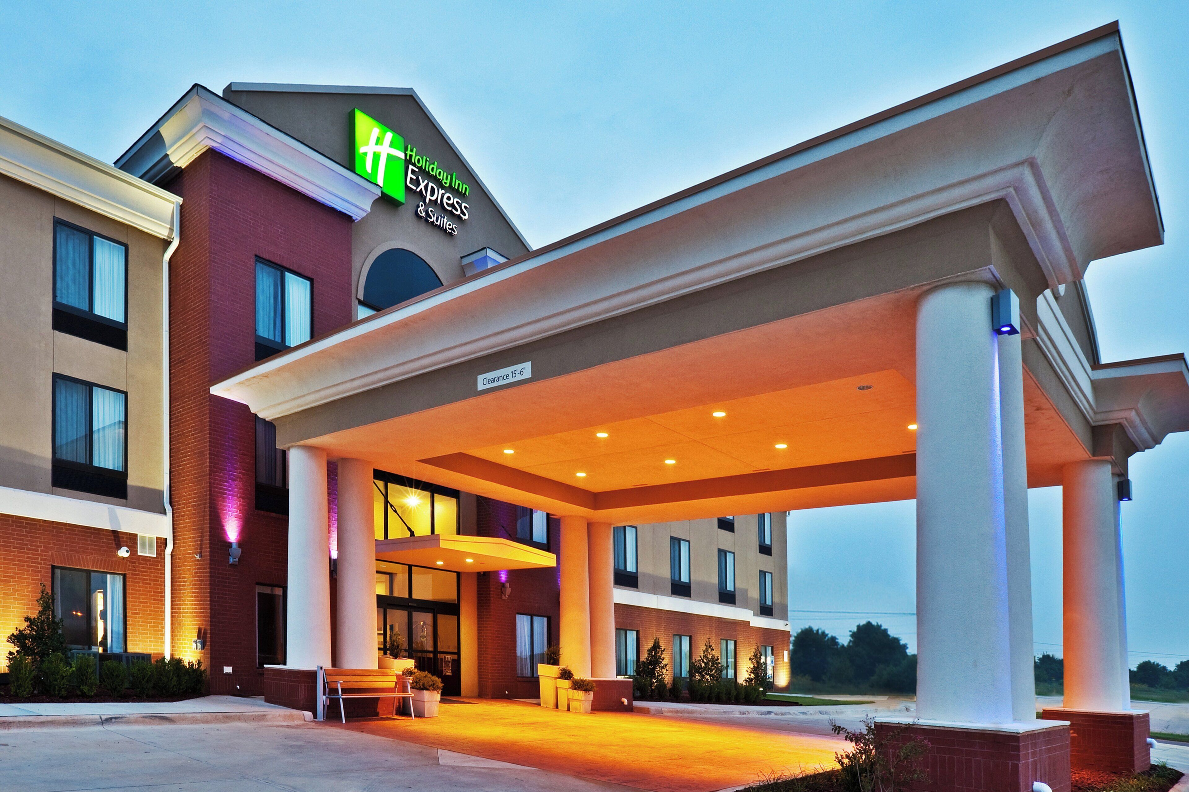 Um hotel Holiday Inn Express & Suites com entrada coberta e placa visível.