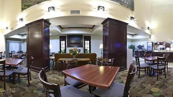Um hall de hotel com área de estar central, balcão de recepção e sala de jantar.