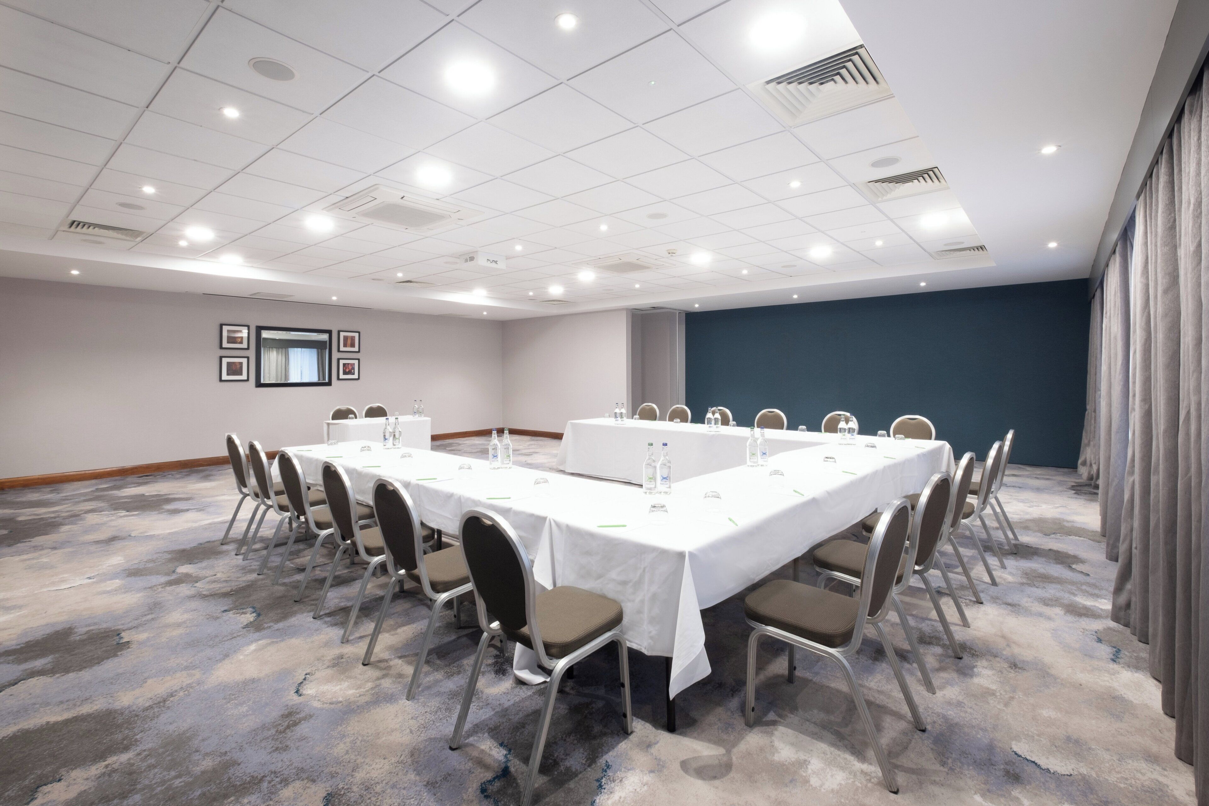Uma sala de conferências com uma mesa comprida, cadeiras e uma tela de projeção na parede.