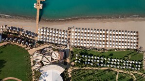 Vista aérea de um resort com várias vilas à beira-mar, área de piscina e praia.
