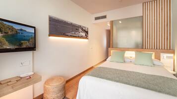 Quarto de hotel com cama, televisão, obra de arte pendurada na parede e design de painel de madeira.
