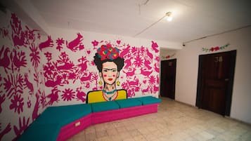 Um quarto com um mural colorido na parede, um banco e duas portas com as indicações 37 e 38.