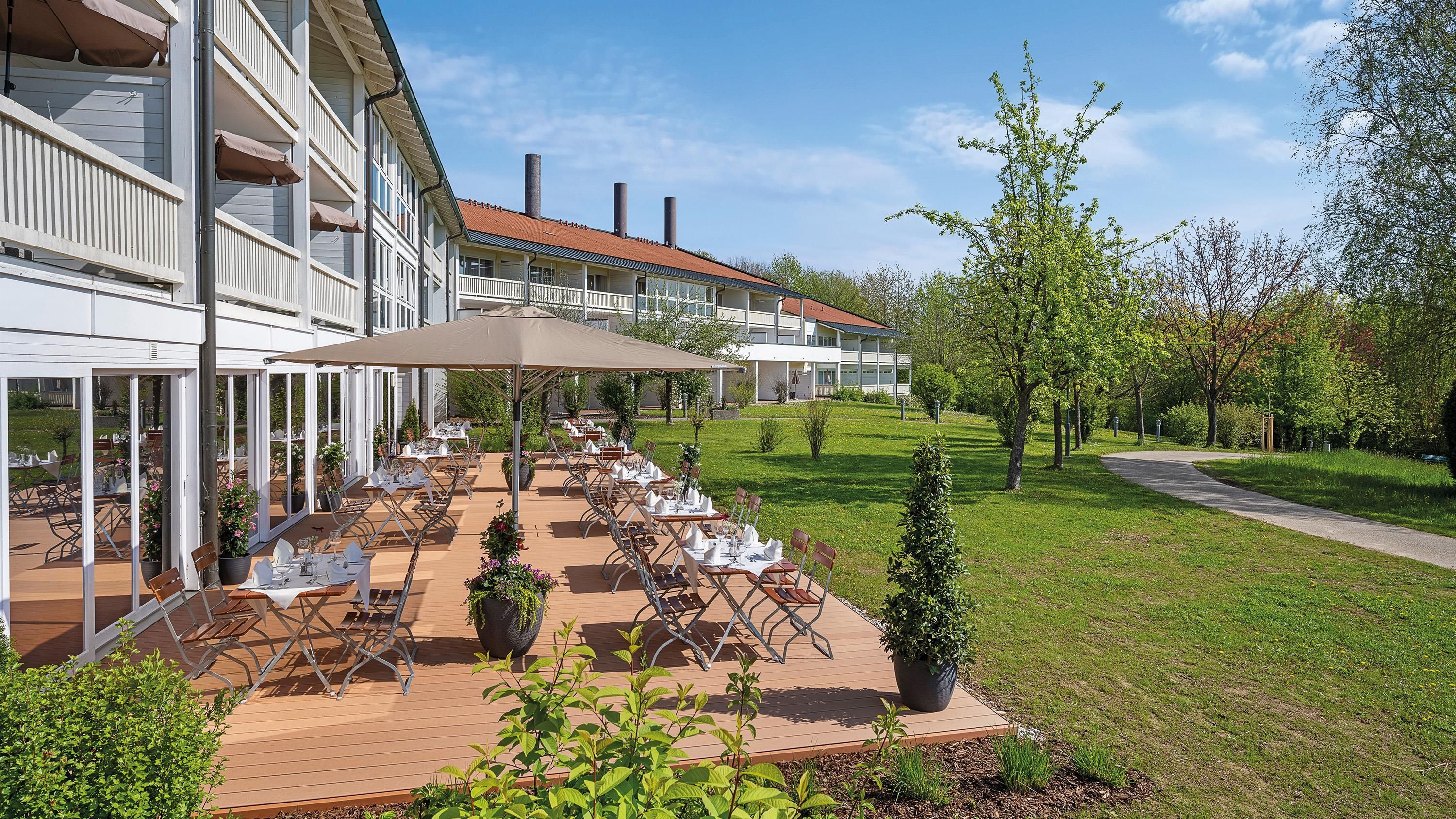 Hotel com área de refeições ao ar livre, vários andares e jardim.