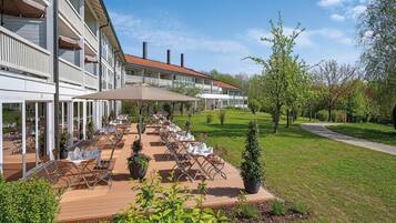 Hotel com área de refeições ao ar livre, vários andares e jardim.