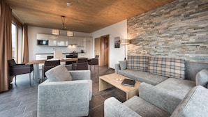 Uma sala de estar moderna com sofás cinza, uma mesa de centro de madeira e uma parede de pedra.