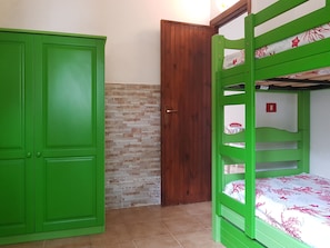 Um quarto com um guarda-roupa verde, uma porta de madeira e uma cama beliche com roupa de cama estampada.