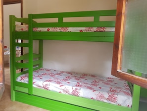 Uma cama beliche com grades verdes e colchão estampado com padrão floral.