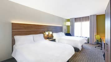 Quarto de hotel com duas camas, uma escrivaninha, uma cadeira e um abajur.