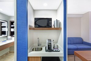 Uma cozinha compacta equipada com micro-ondas, cafeteira e pia.