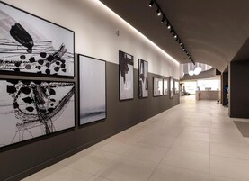 Um corredor com uma série de obras de arte emolduradas nas paredes, piso ladrilhado e design de teto moderno.