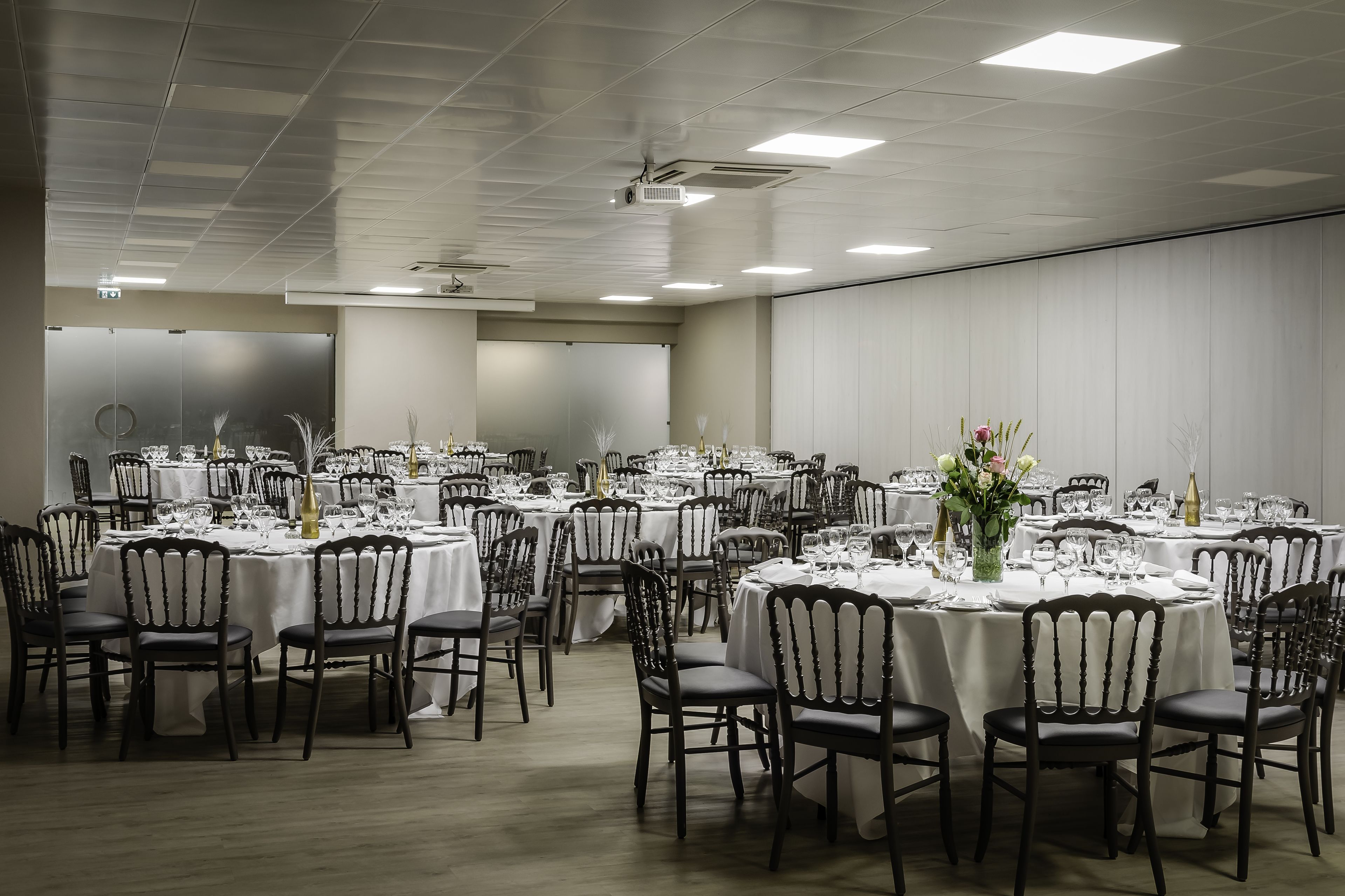 Uma sala de conferências com várias mesas redondas, cada uma disposta com cadeiras e louças.