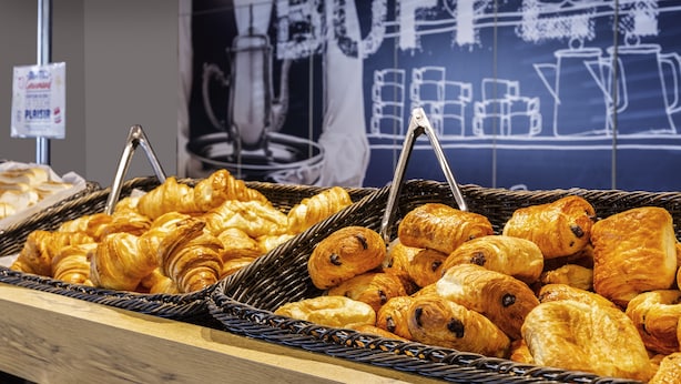 Exposição de diversos doces e pastéis em cestas de vime, com um quadro negro ao fundo que diz 'BUFFET'.