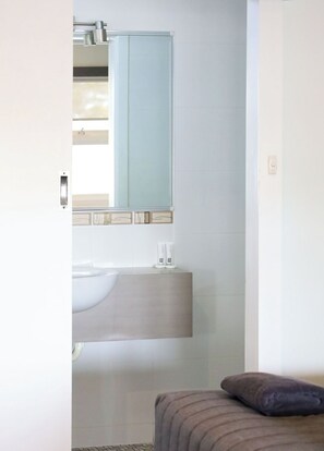 Um banheiro com design moderno, apresentando um espelho grande, uma pia e um vaso sanitário.