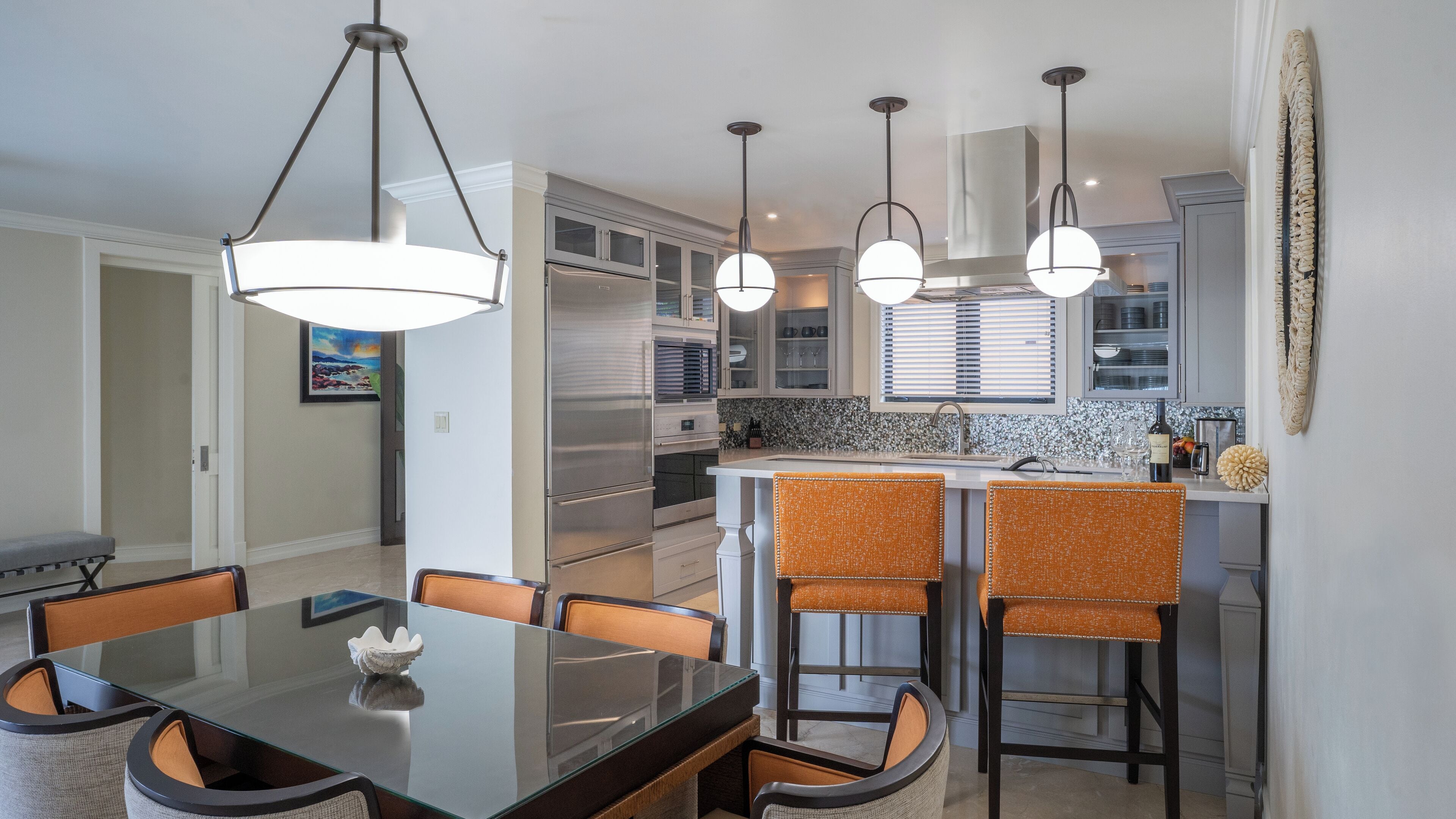 Uma cozinha moderna com eletrodomésticos de aço inoxidável, uma ilha central com banquetas e iluminação pendente.
