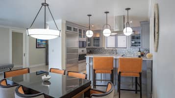 Uma cozinha moderna com eletrodomésticos de aço inoxidável, uma ilha central com banquetas e iluminação pendente.