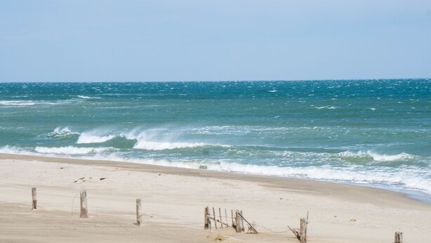 Uma praia com ondas e céu claro.