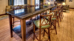 Uma sala de jantar ampla com uma mesa comprida, várias cadeiras, uma televisão e uma lareira.