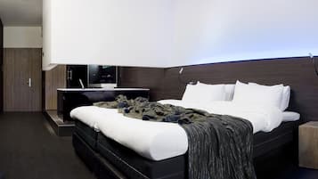 Quarto de hotel moderno com uma cama grande, televisão de tela plana, escrivaninha e uma parede de destaque em madeira.