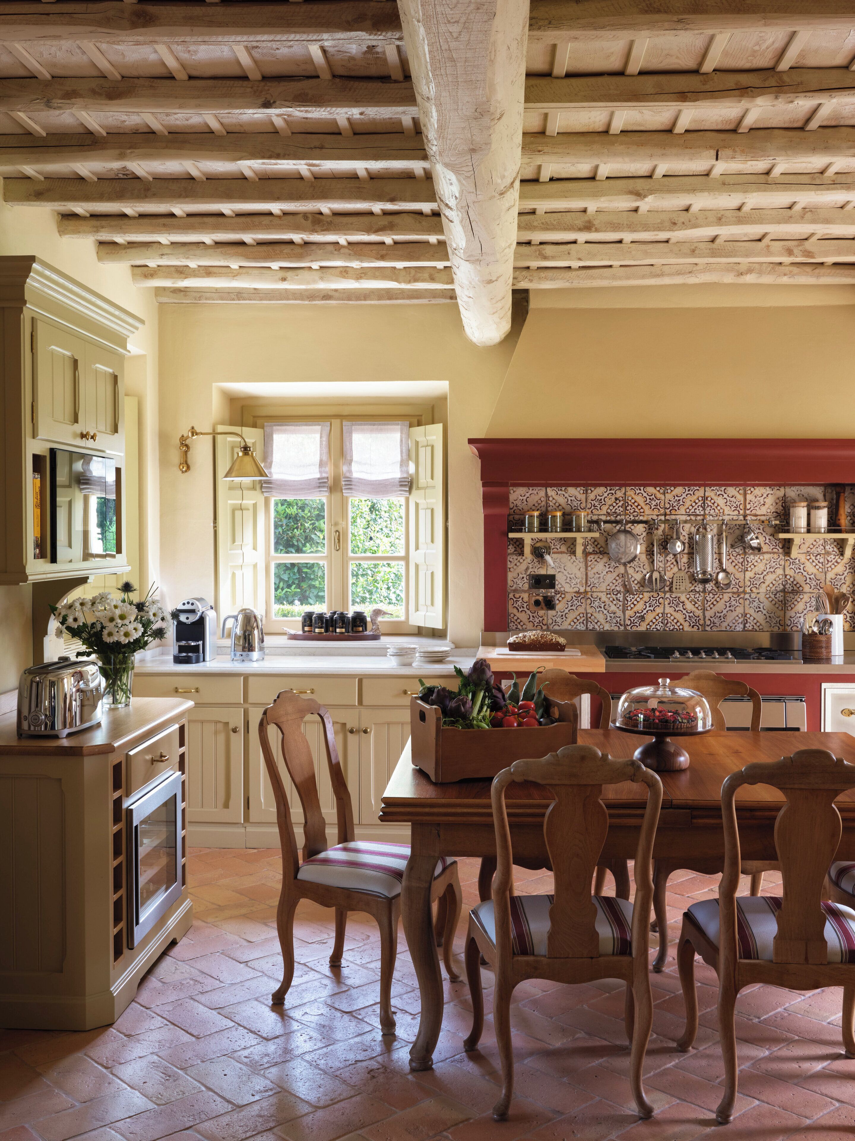 Cozinha com armários de madeira, mesa de jantar com cadeiras, janela com cortinas e painel de azulejos.