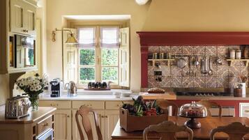 Cozinha com armários de madeira, mesa de jantar com cadeiras, janela com cortinas e painel de azulejos.