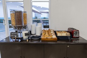 Buffet de café da manhã com cereais, leite e pães.