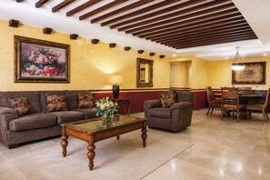 Uma sala de estar ampla, com sofás, uma mesa de centro e uma mesa de jantar com cadeiras.