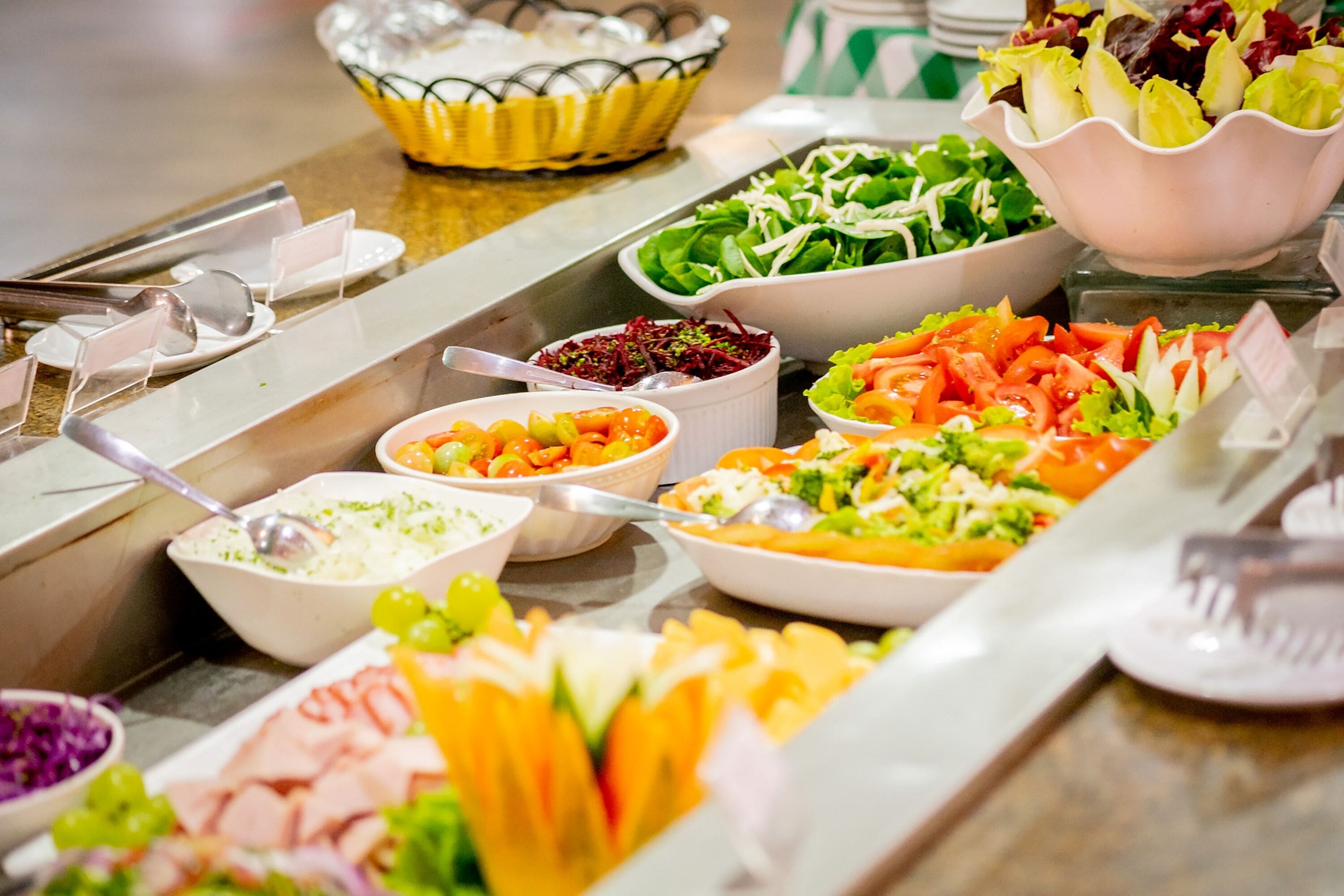 Buffet com diversos pratos, incluindo saladas, carnes e legumes.