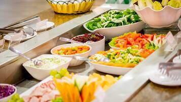 Buffet com diversos pratos, incluindo saladas, carnes e legumes.