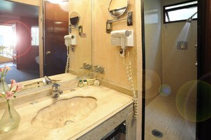 Casa de banho com lavatório, espelho, secador de cabelo e chuveiro.