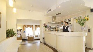 Um saguão de hotel com balcão de recepção, um sofá e uma área de refeições.