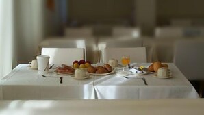 Mesa de café da manhã posta com pratos de comida, xícaras e um copo de suco de laranja em um quarto de hotel.