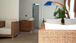 Quarto com móveis de vime, uma cama, abajur azul e um vaso de planta.