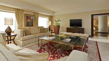 Uma sala de estar moderna com sofá, poltronas, mesa de centro, televisão e uma janela grande com cortinas.