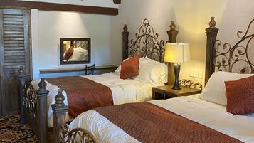 Quarto de hotel com duas camas, cabeceiras de madeira, carpete estampado e teto com vigas aparentes.