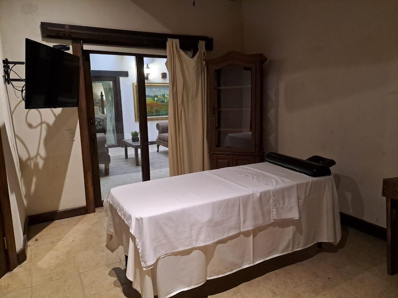 Quarto com cama, televisão fixada na parede, armário e porta de vidro deslizante para área externa.