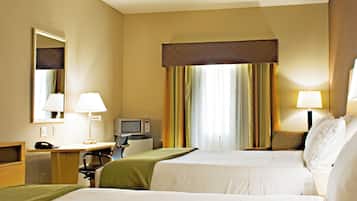 Quarto de hotel com duas camas, uma escrivaninha com telefone, televisão e janela com cortinas.
